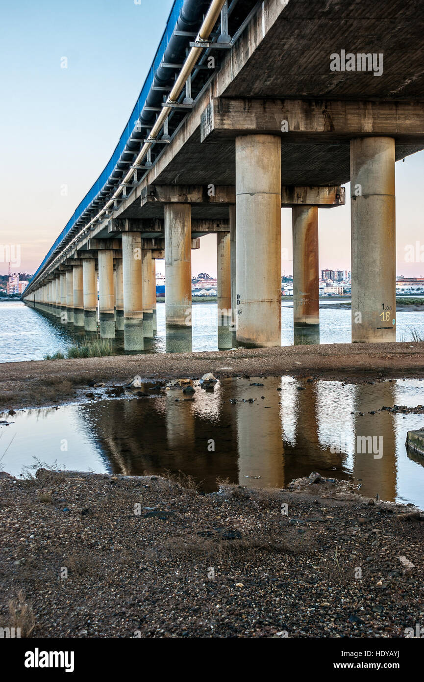Under a bridge a puddle with the reflection of the bridge on the same ...