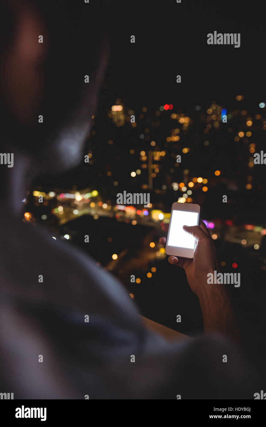 Rear view of man using his mobile phone in the balcony at night Stock ...