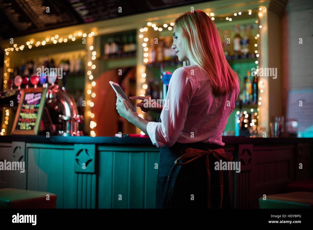 Beautiful waitress using a digital tablet in bar Stock Photo - Alamy