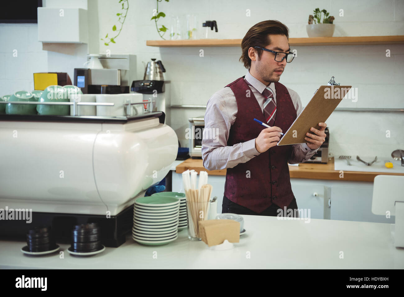 Man writing with pen on clipboard in coffee shop Stock Photo - Alamy