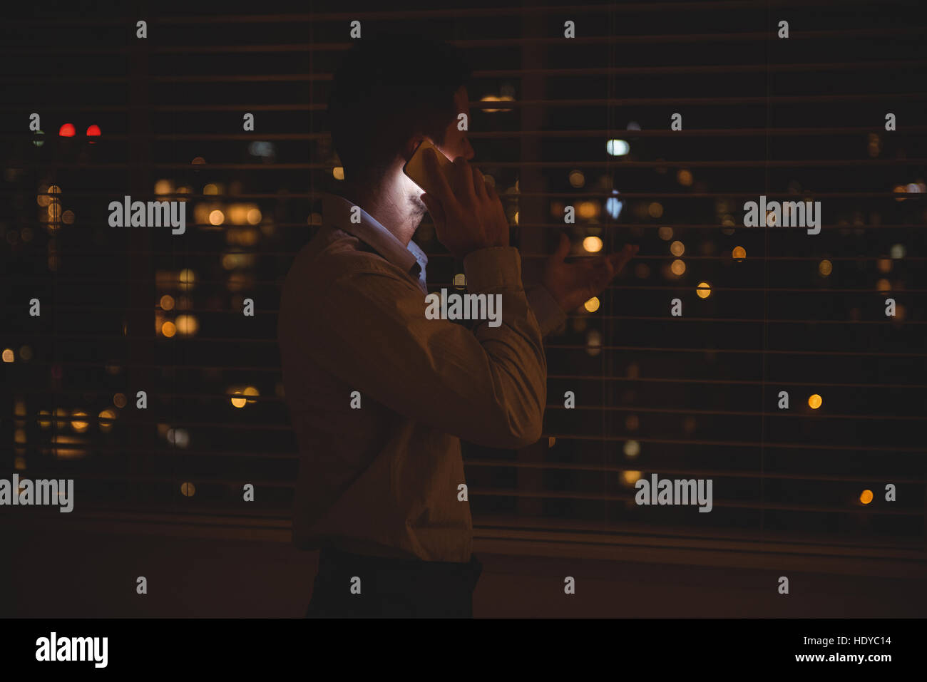 Man looking through window while talking on mobile phone at night Stock ...