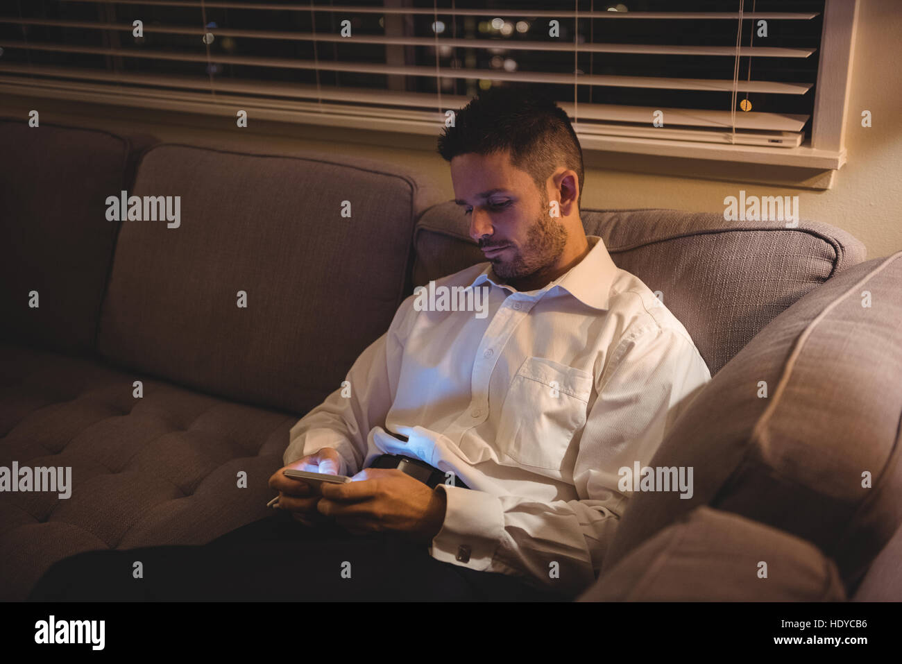 Man using his mobile phone in living room at home Stock Photo - Alamy