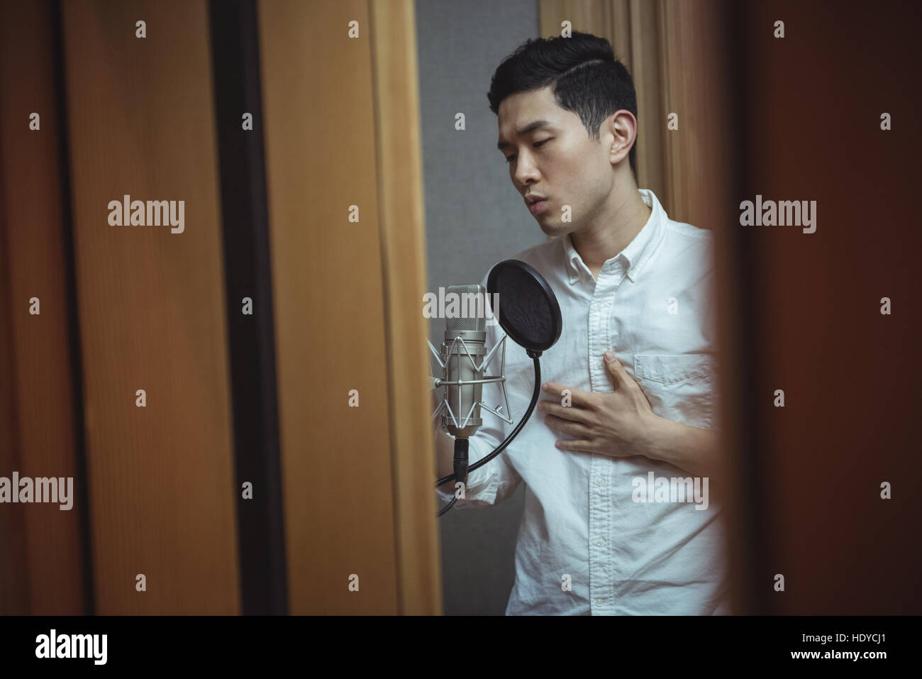 Man singing on microphone in recording studio Stock Photo - Alamy