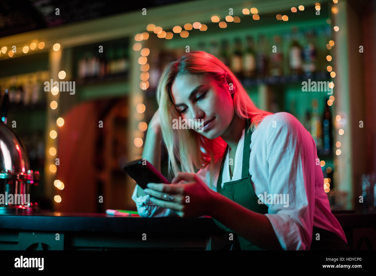 Waitress using her mobile phone at the bar counter Stock Photo - Alamy