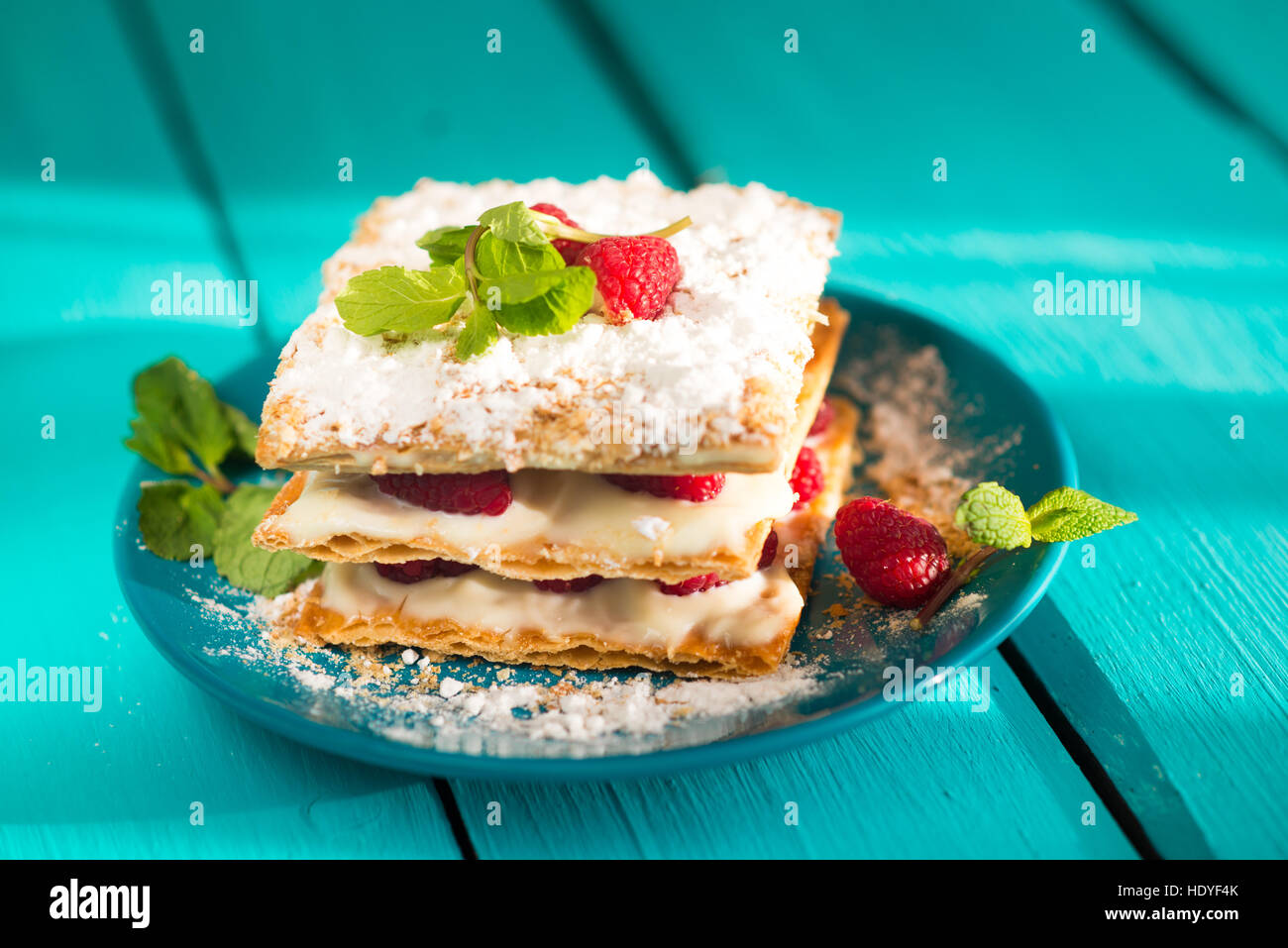 Mille-feuille of puff pastry with raspberries on a wooden Board cyan ...