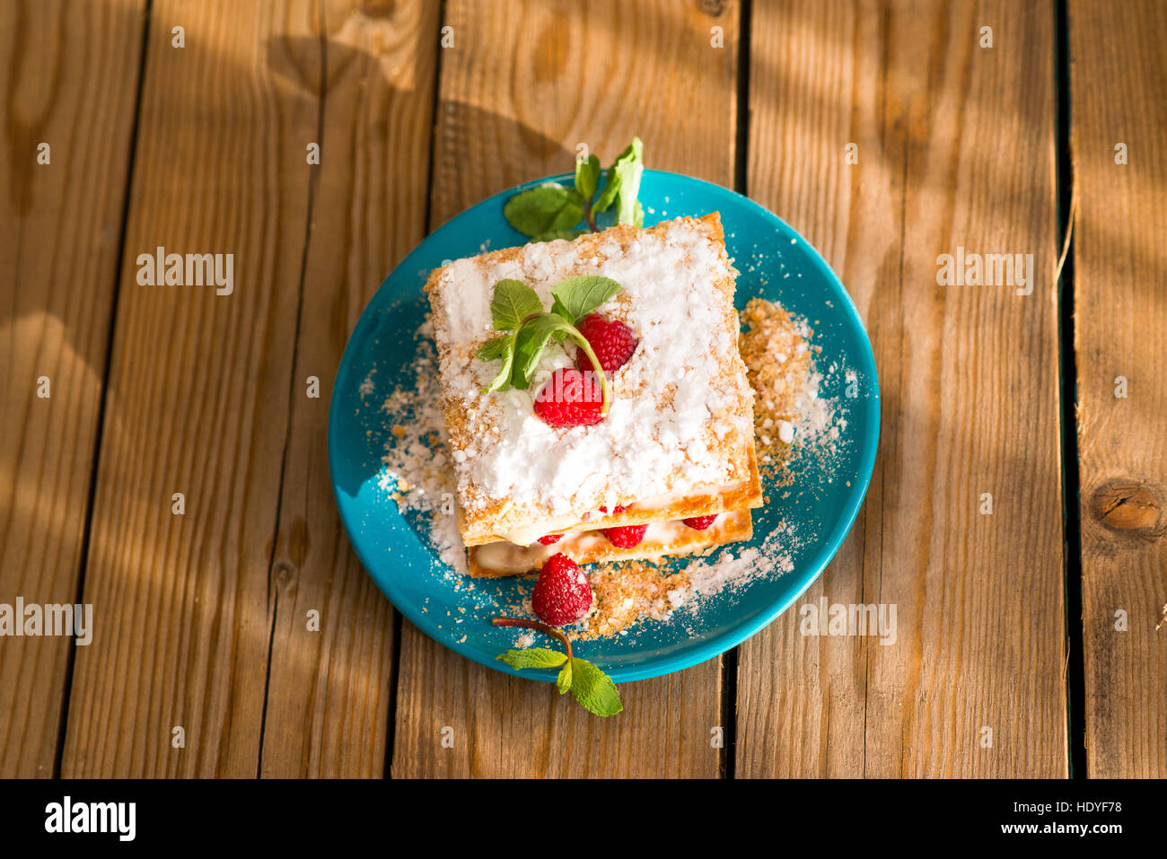 Mille-feuille of puff pastry with raspberries on a wooden Board cyan ...