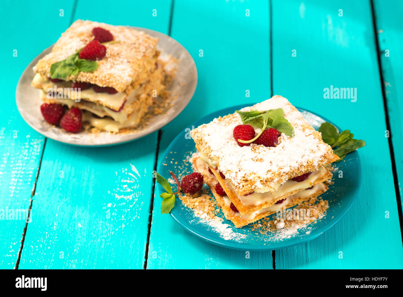 Mille-feuille of puff pastry with raspberries on a wooden Board cyan ...