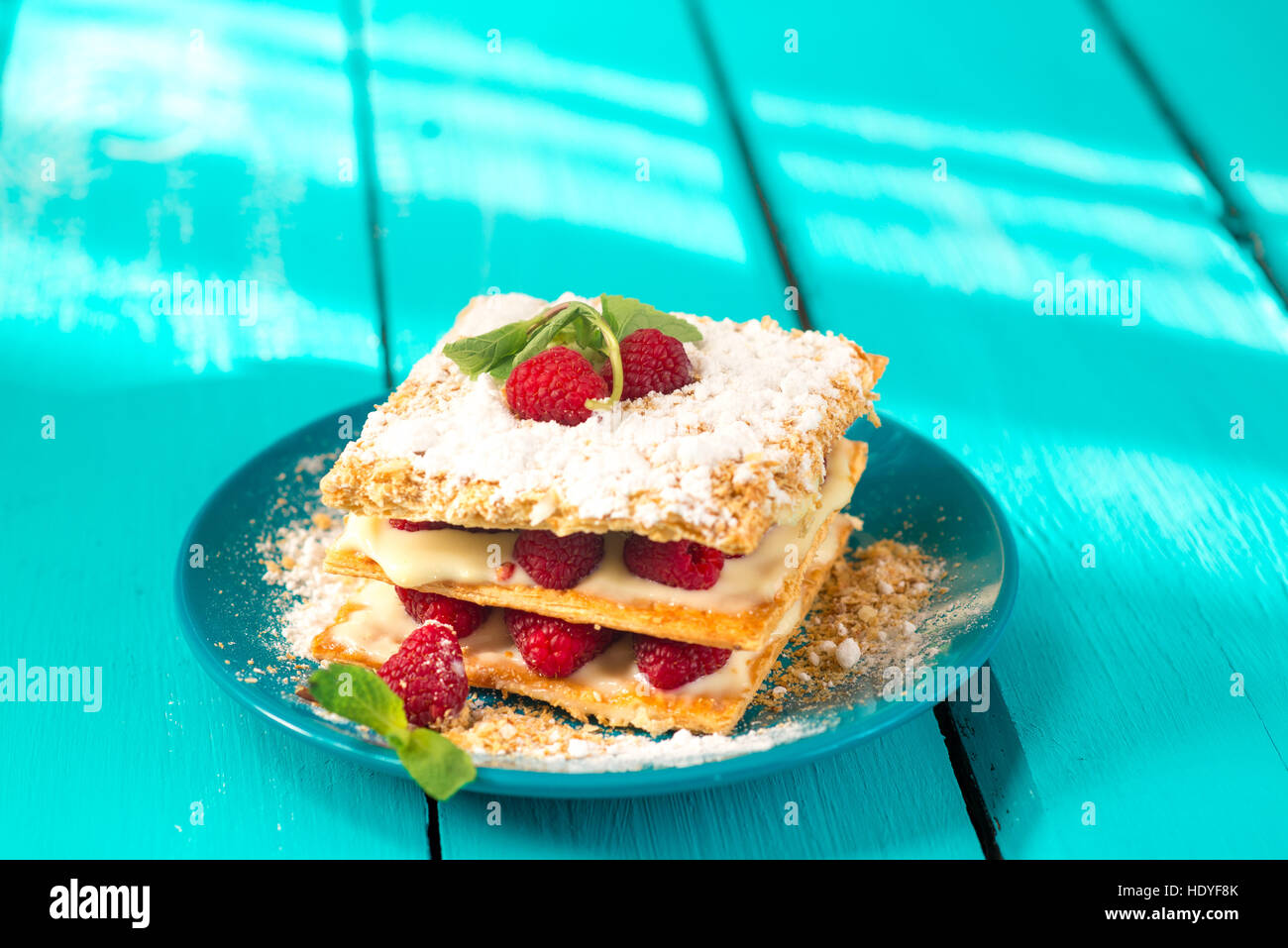 close up of Mille-feuille puff pastry with raspberries on a blue Board ...