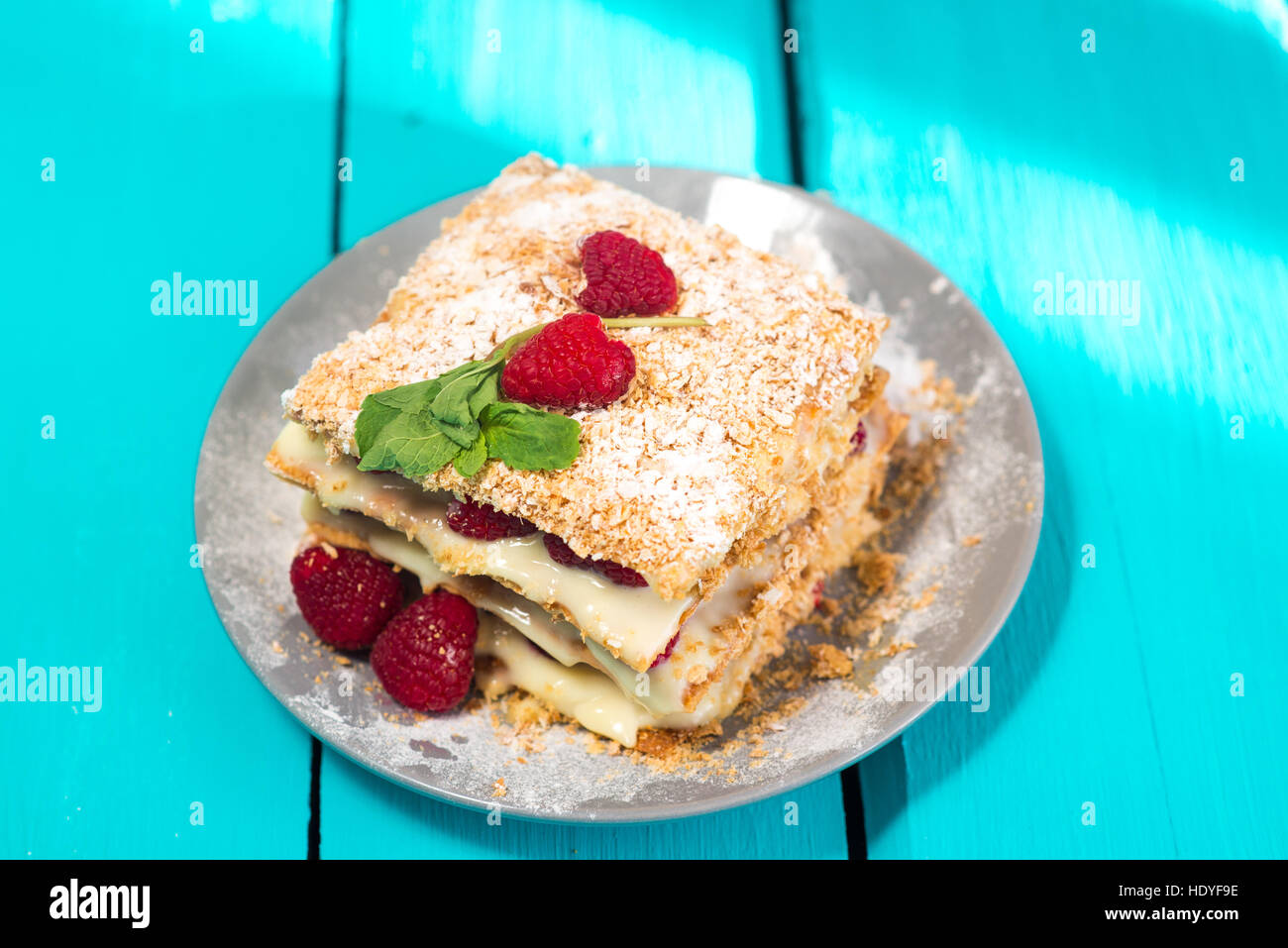 Mille-feuille of puff pastry with raspberries on a wooden Board cyan ...