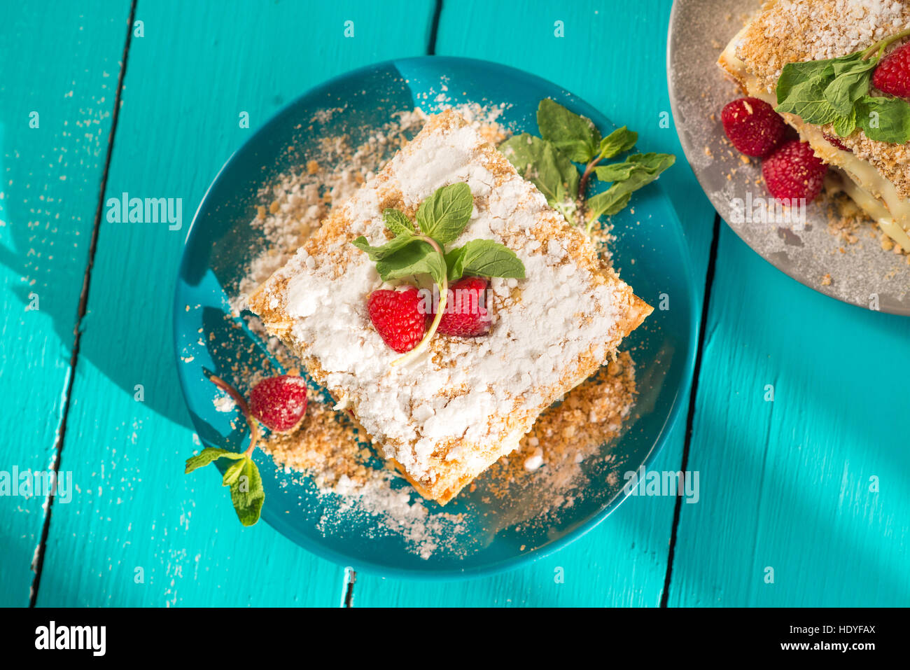 close up of Mille-feuille puff pastry with raspberries on a blue Board ...