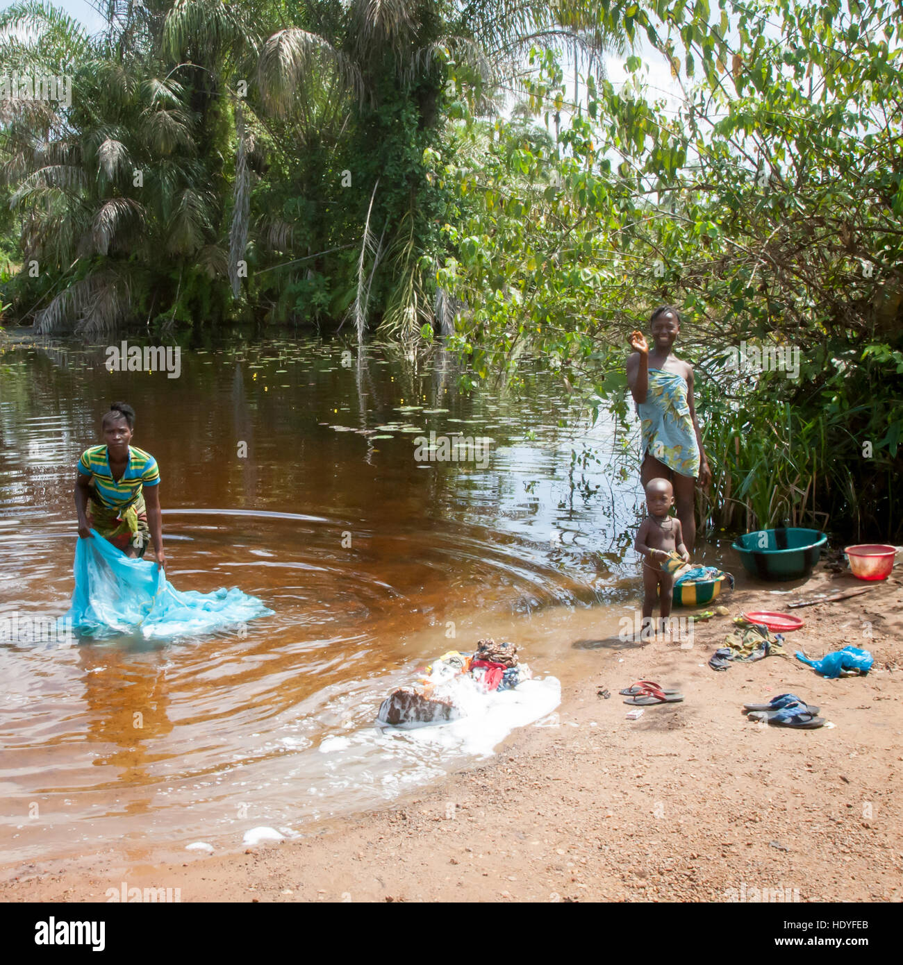 Two women cleaning body, baby and clothes in the water of a river. It ...