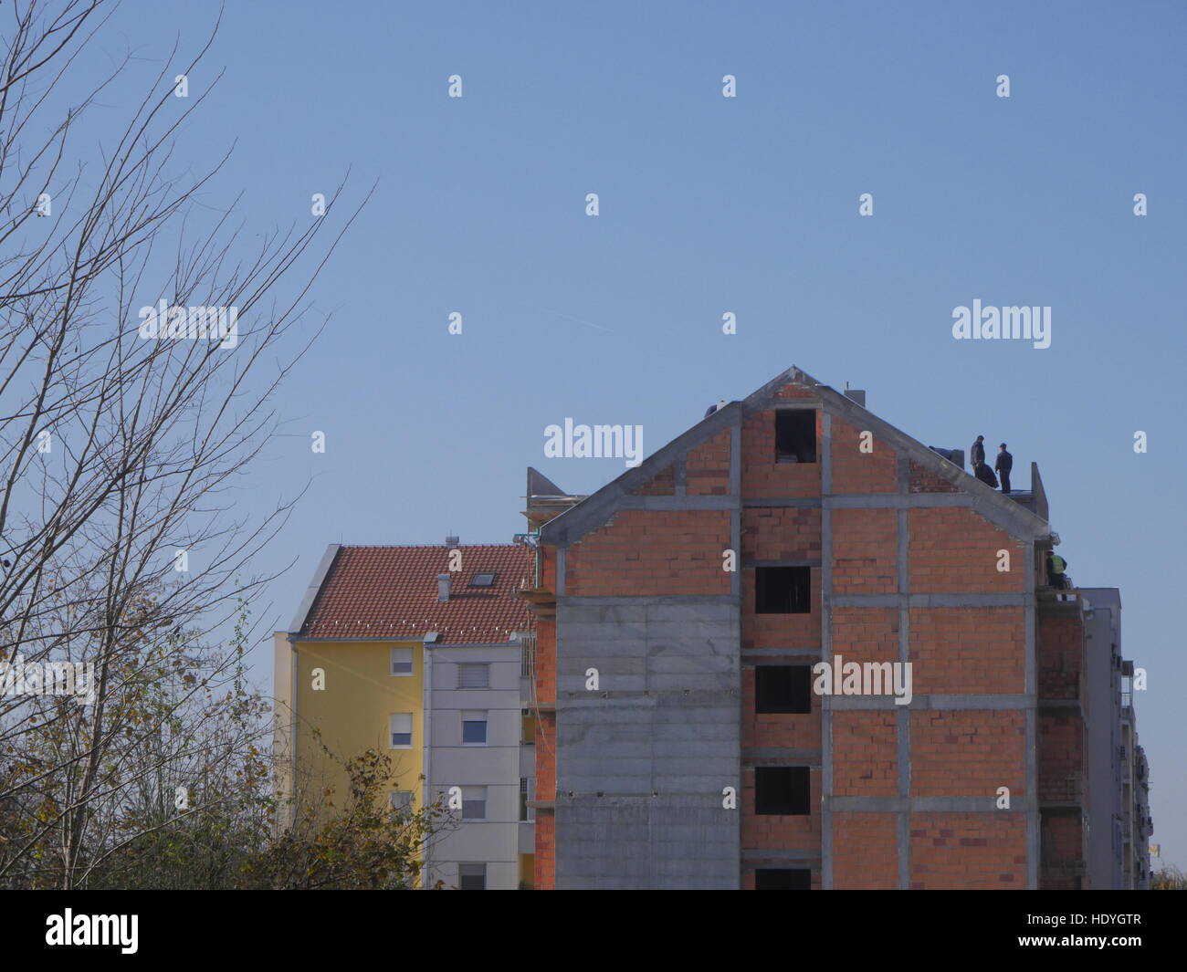 Distant construction workers on top of the building Stock Photo - Alamy