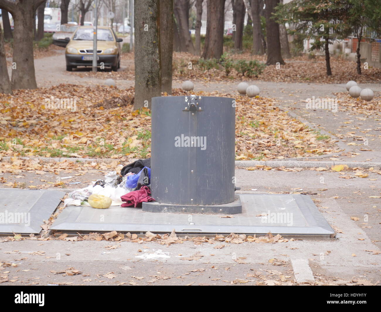 Garbage can with old clothes on the side Stock Photo - Alamy