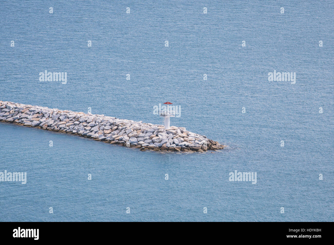 Lighthouse on edge of white bridge made from stone floating on blue sea ...