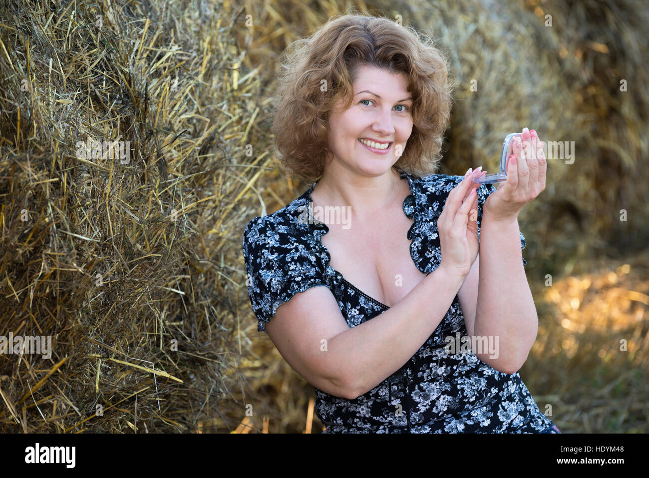 Woman powder oneself in field on a background of straw bales Stock ...