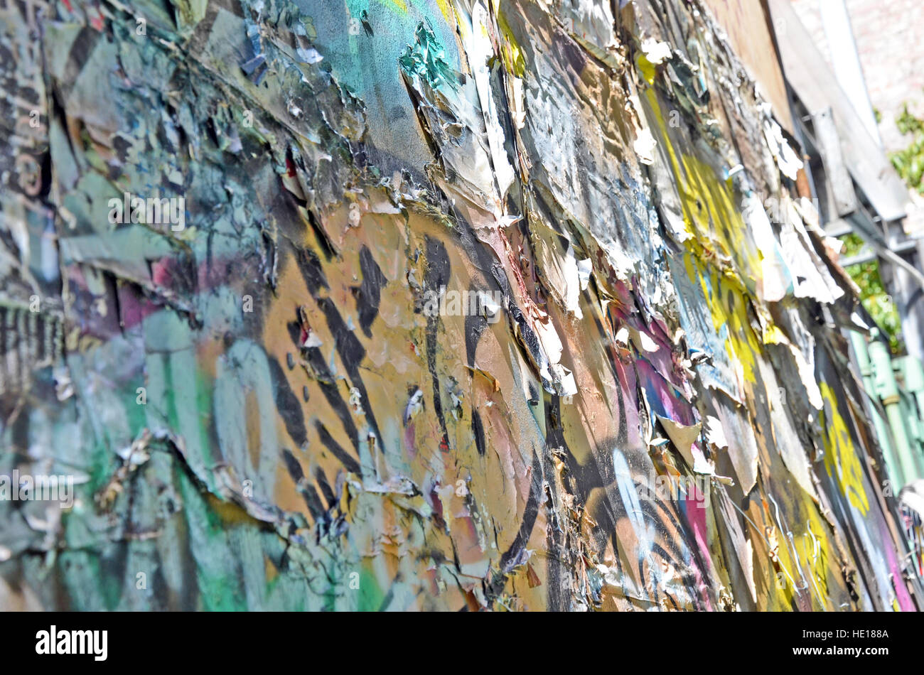 Alley wall with layers of old peeling and torn colorful posters in ...