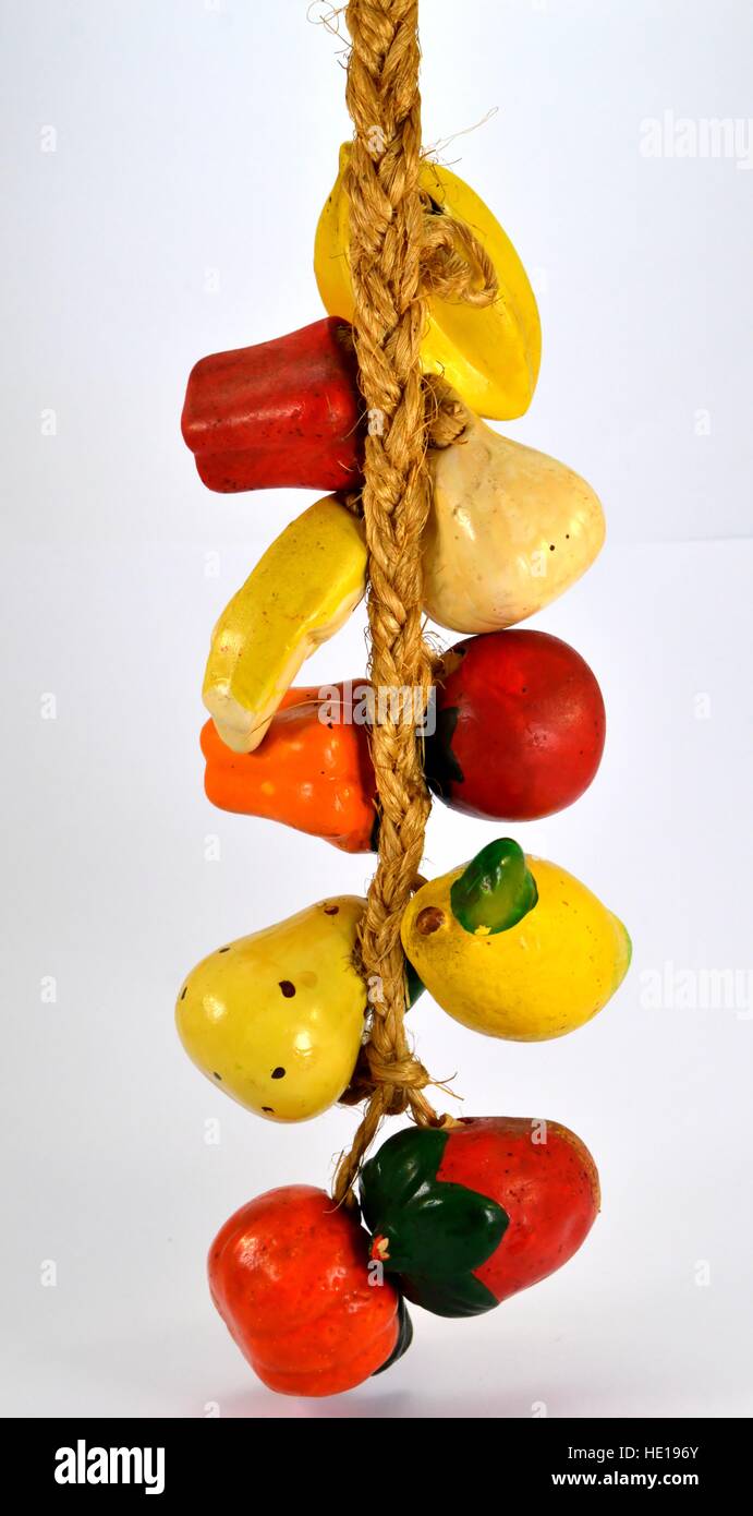 Several fruits and vegetables in bunch on a rope on a white background ...