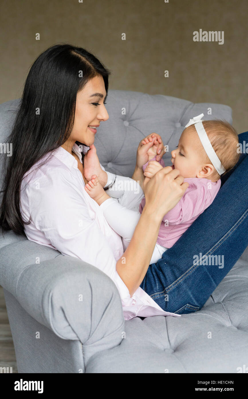 Mother is sitting with baby on an armchair Stock Photo - Alamy