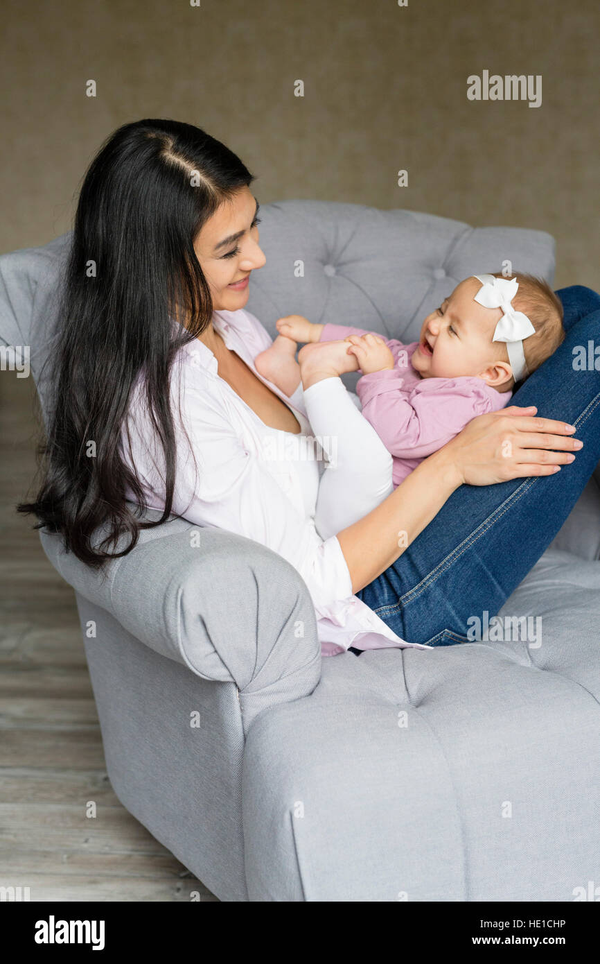 Mother is sitting with baby on an armchair Stock Photo - Alamy