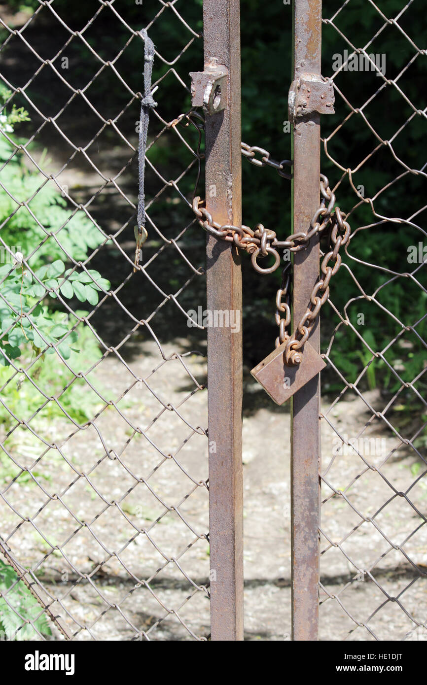 metal lock closes the gate with a chain and key is hanging near Stock ...