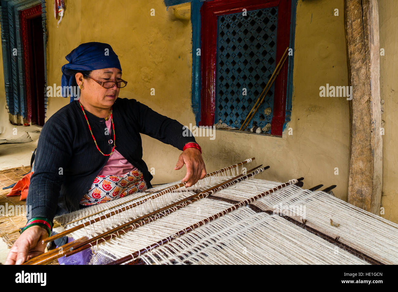 A local woman is weaving a blanket, using sheep wool, in front of a ...