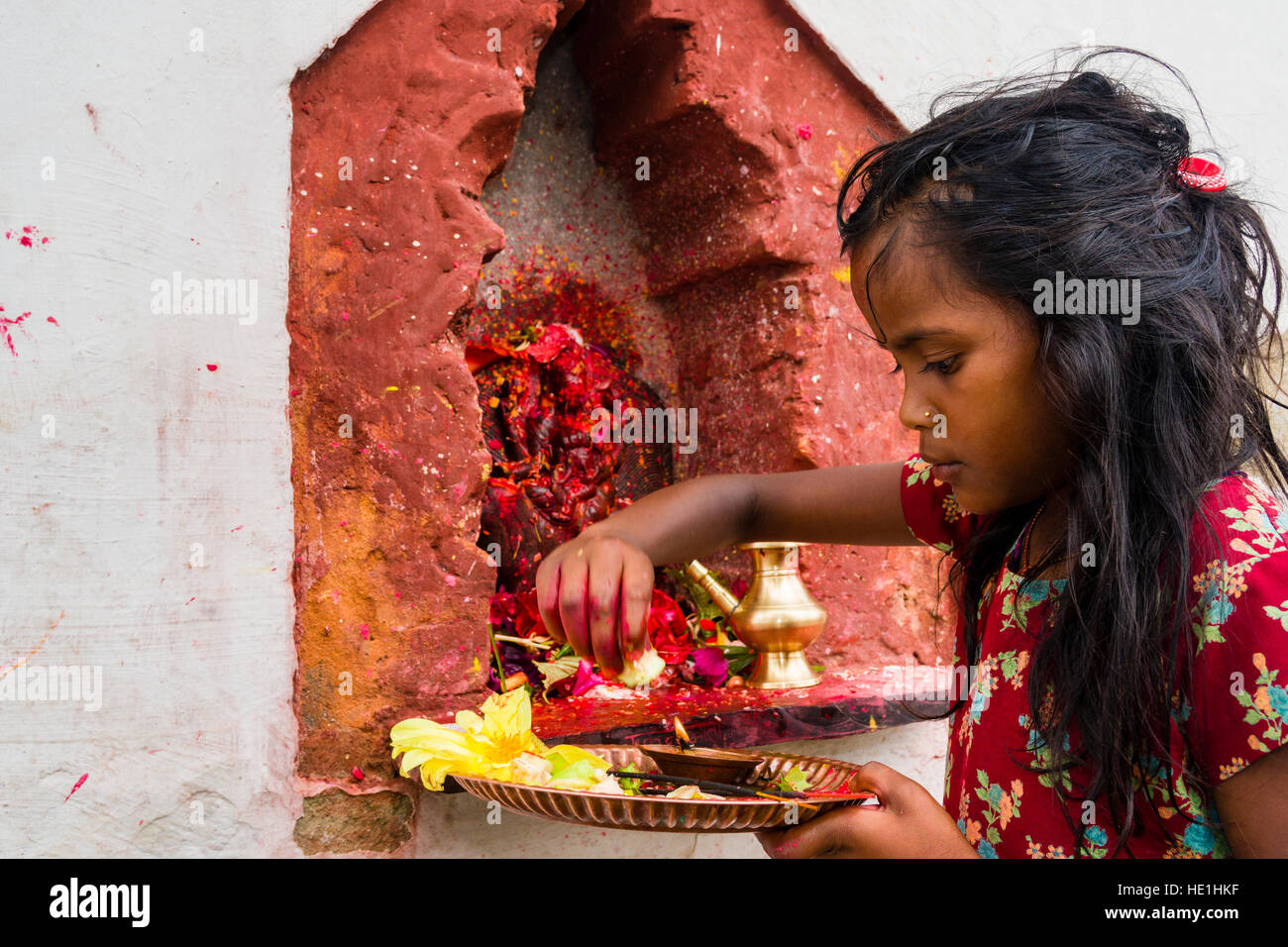 A little girl is offering prasad to the statues of gods outside the ...