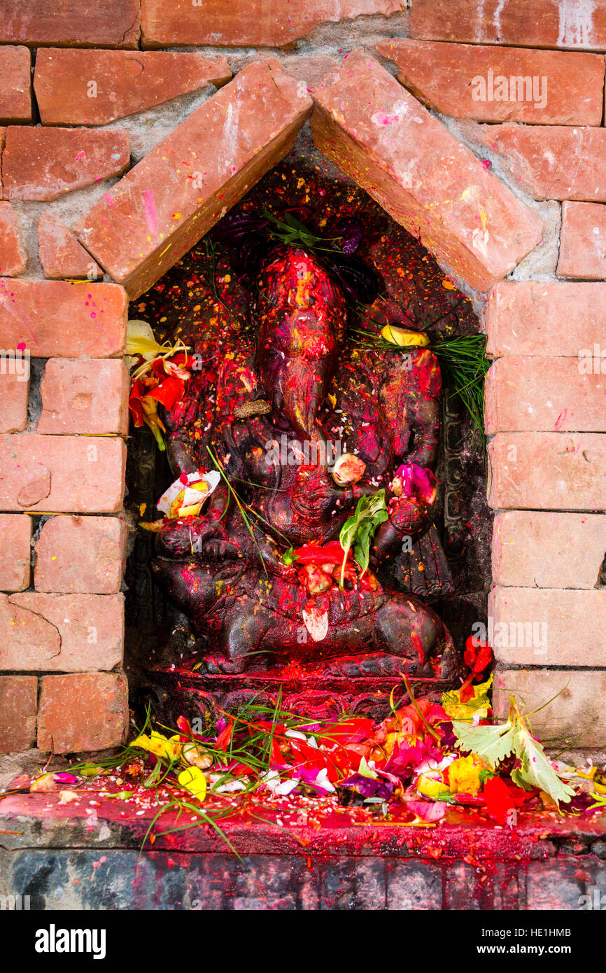 A small statue of the god Ganesh is colorfully decorated outside the ...
