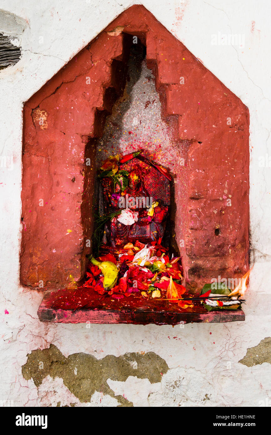 A small statue of the god Maha Gauri is colorfully decorated outside ...