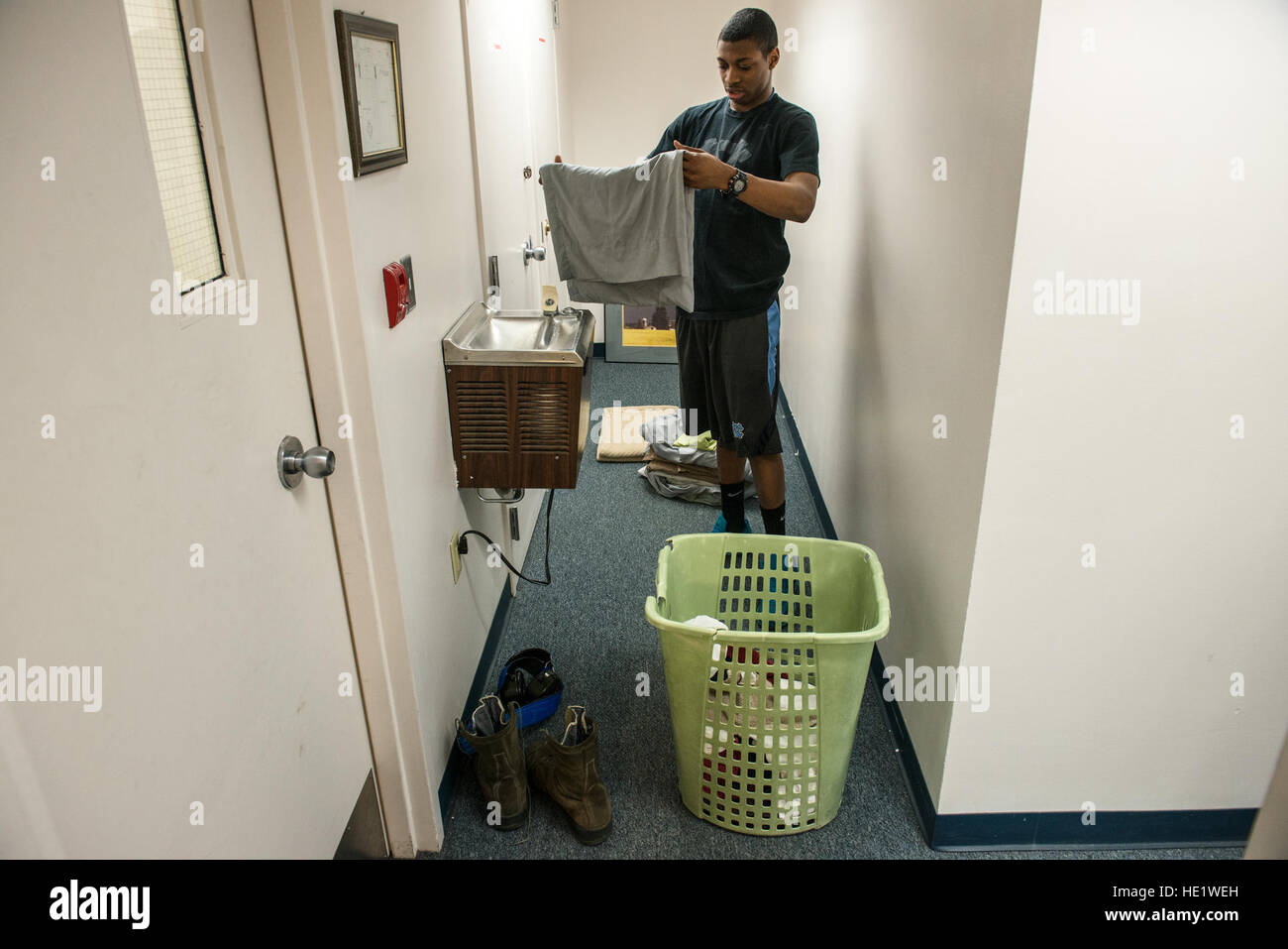 Airman 1st Class Avian Sharpe folds laundry in the hallway of the ...