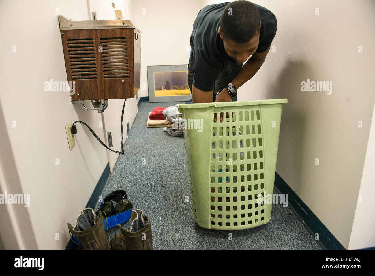 Airman 1st Class Avian Sharpe folds laundry in the hallway of the ...