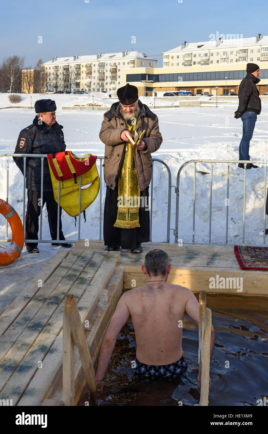 Priest consecrates the ice hole. Man bathes into cold water of ice-hole ...