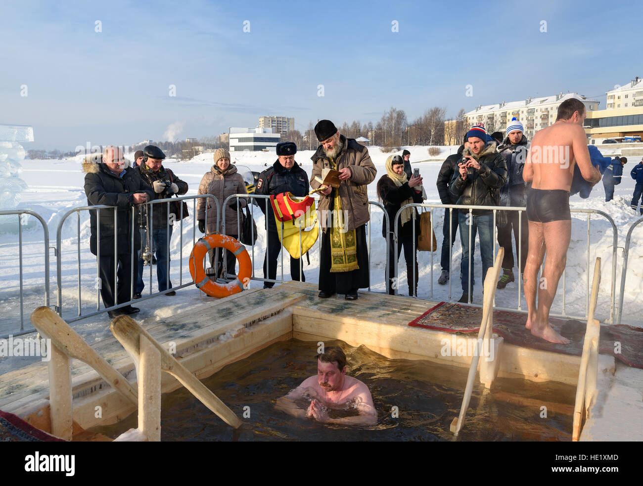 Priest consecrates the ice hole. Man bathes into cold water of ice-hole ...