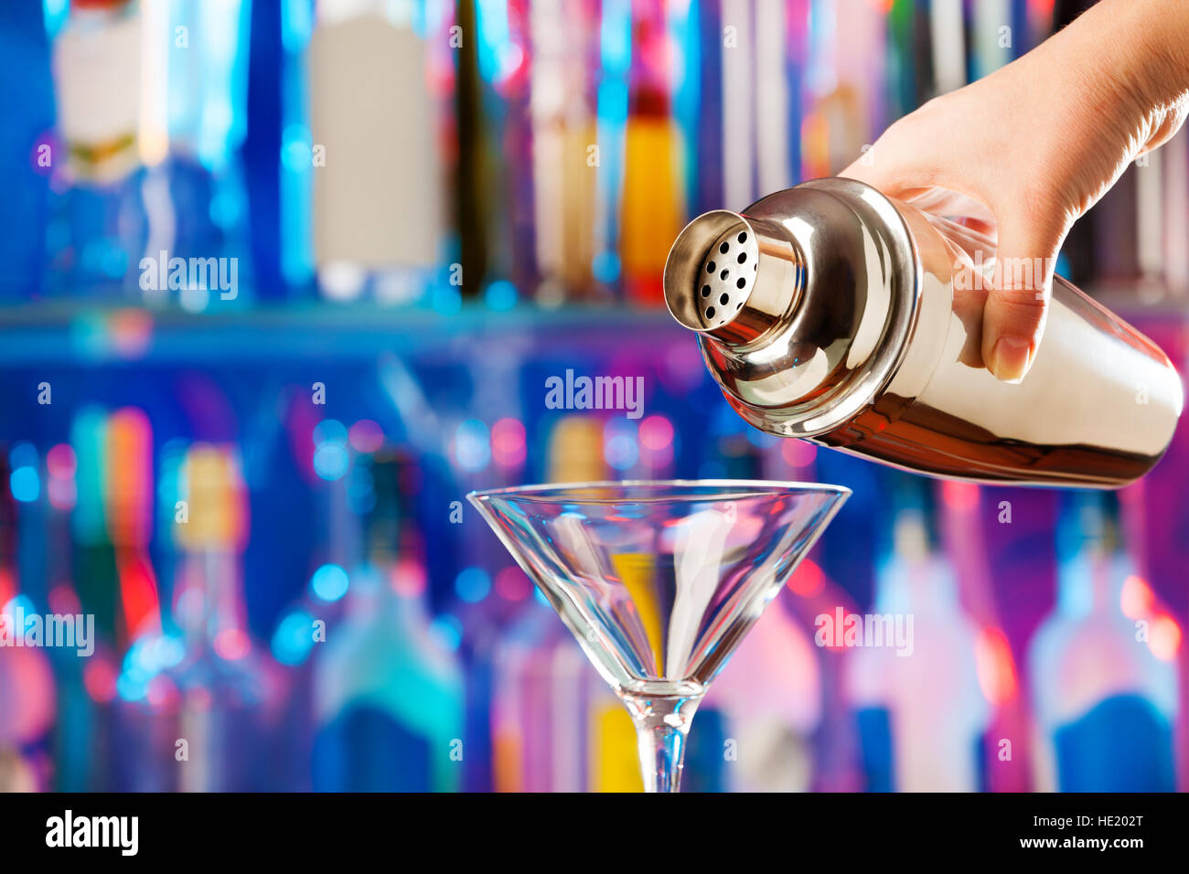 Barman hand pouring drink into a cocktail glass Stock Photo - Alamy