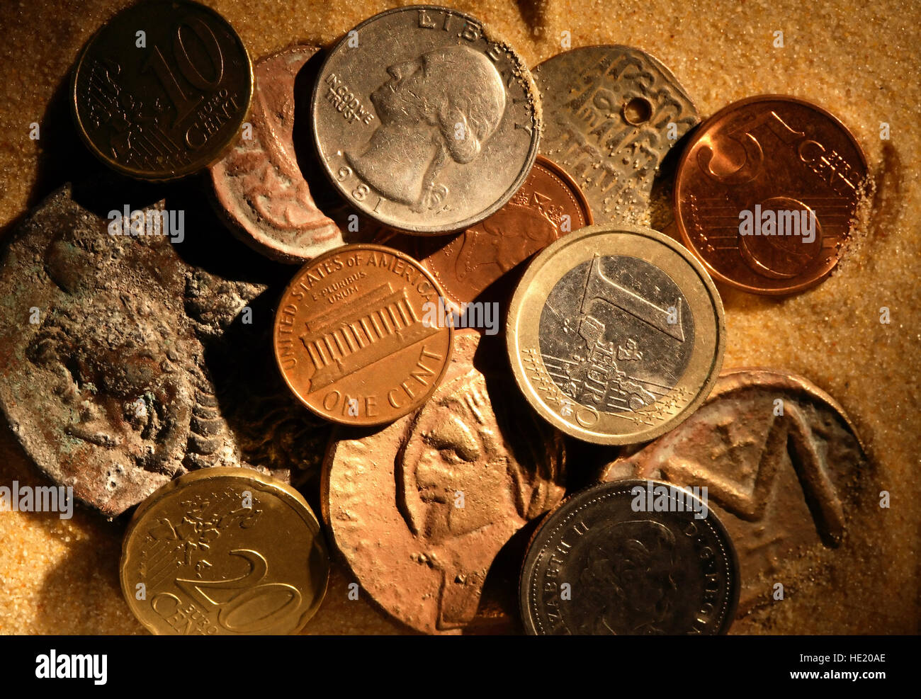 Business concept. Various modern and ancient coins on sand surface ...