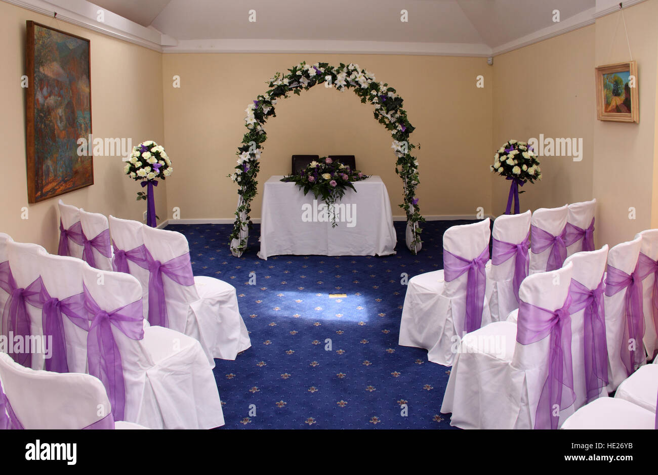 A room laid ready for a wedding ceremony, with an arch of flowers, and ...