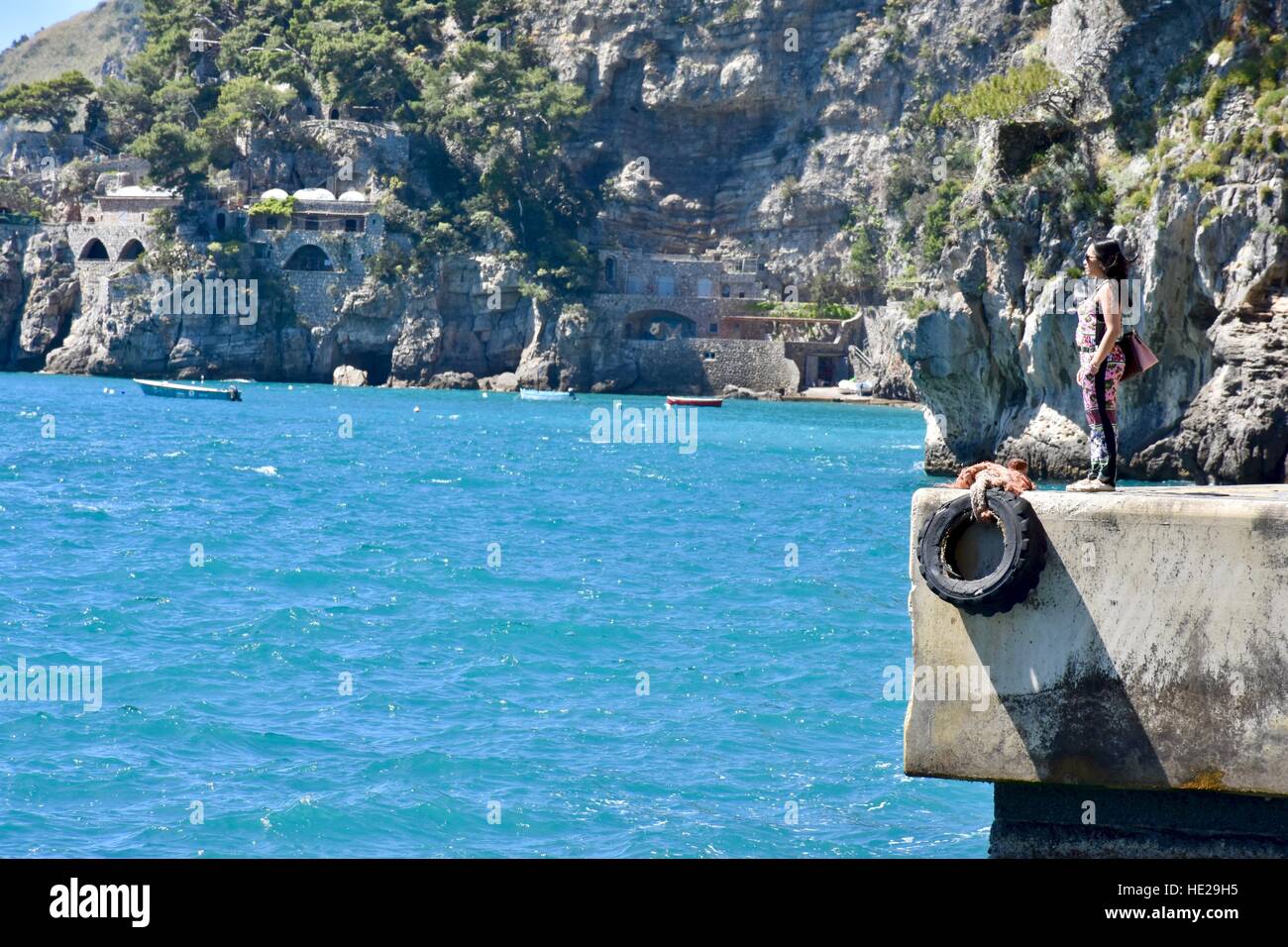 A woman standing out on the edge of an old ship port while looking out ...