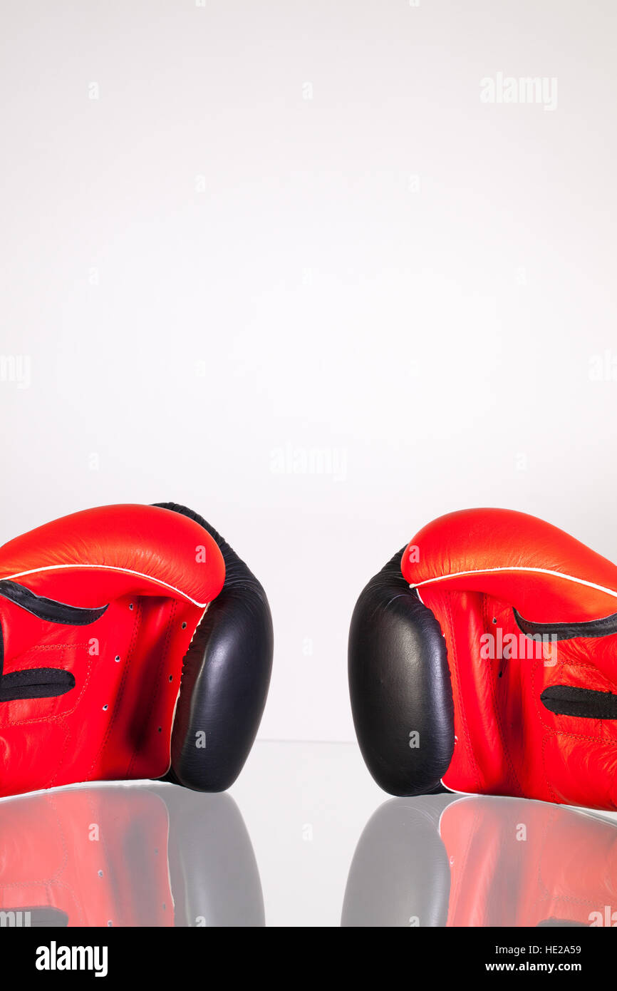 Red and black boxing gloves on a glass table isolated on white ...