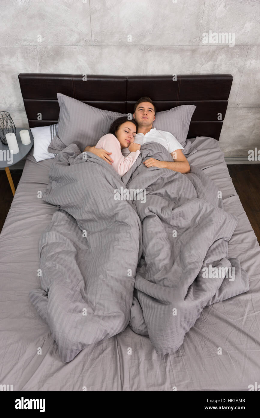 Young couple hugging each other while sleeping in the bed and wearing ...