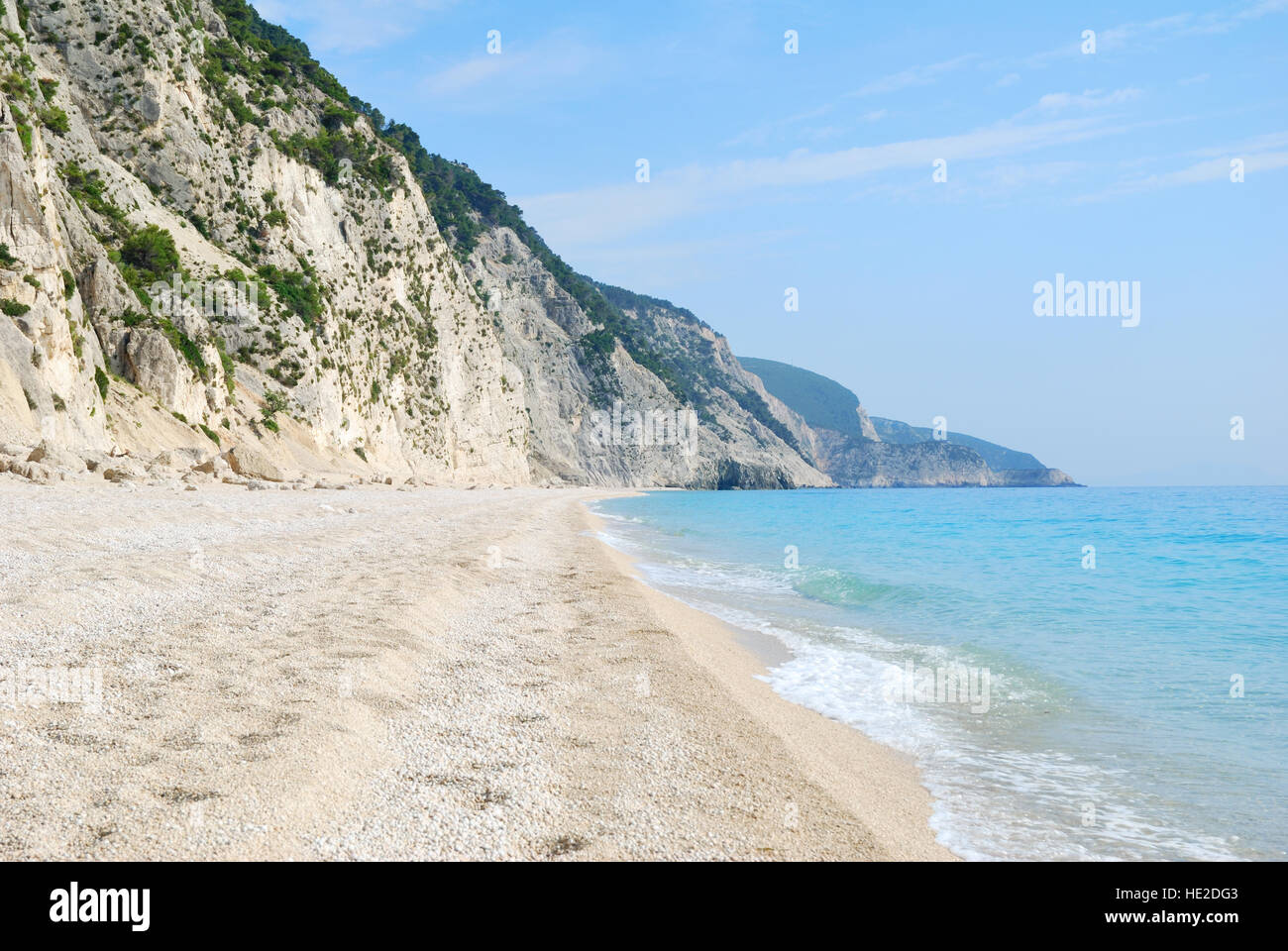 Long wide beach with steep cliffs and clean blue sea Stock Photo - Alamy