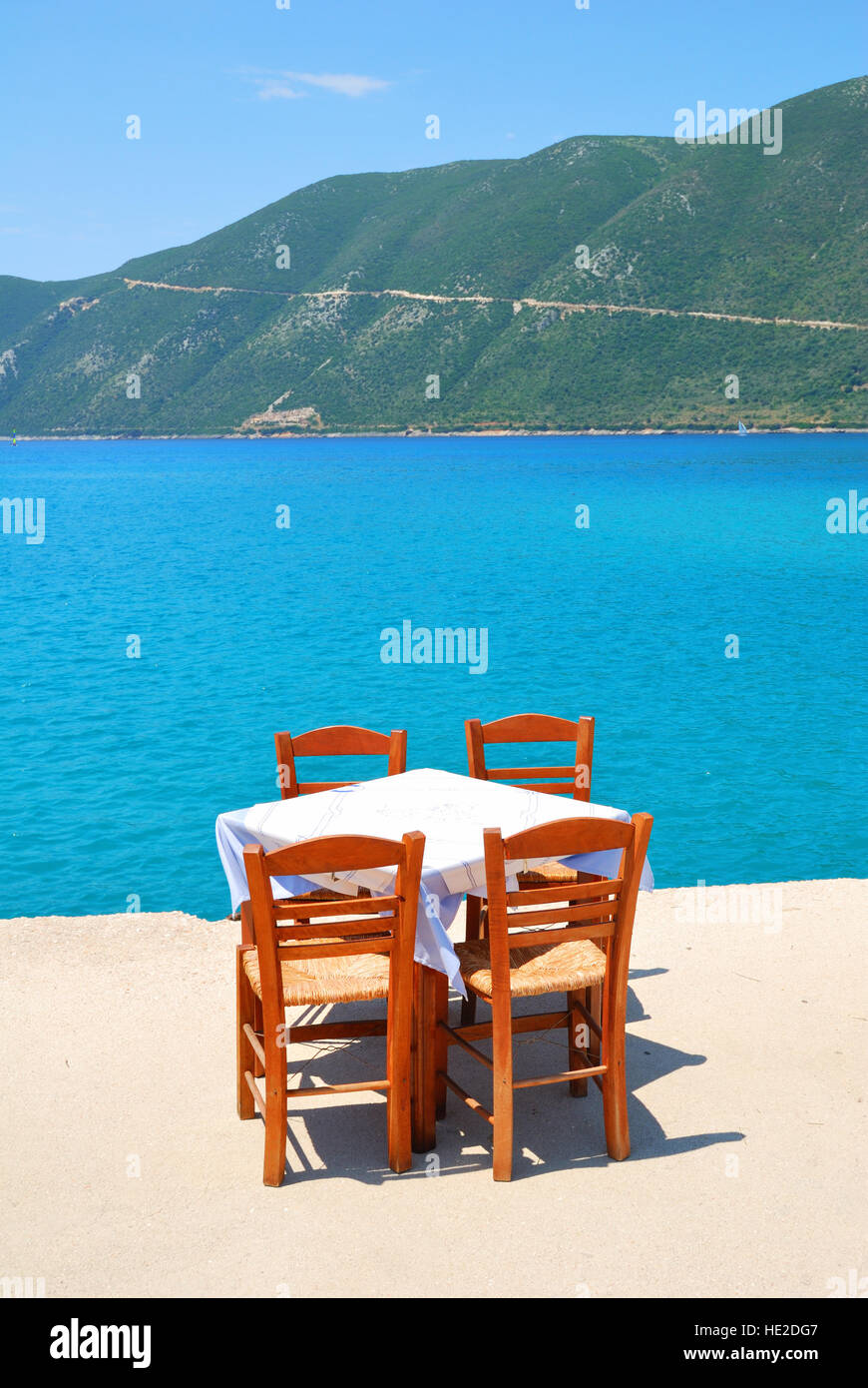 Dining table with chairs in a greek taverna with blue sea and green ...