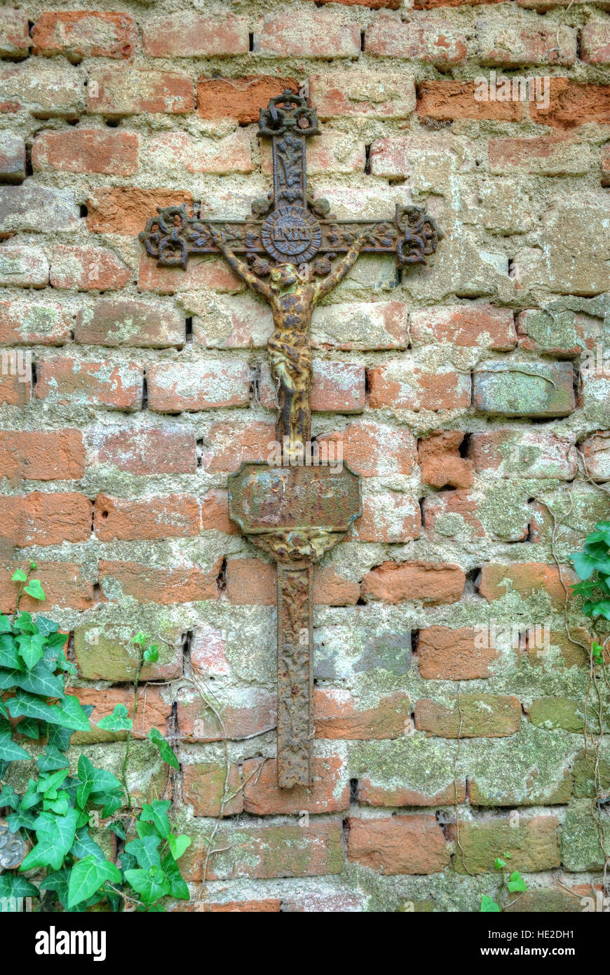 Rusty christian cross with Jesus Christ statue hanging on an old brick ...