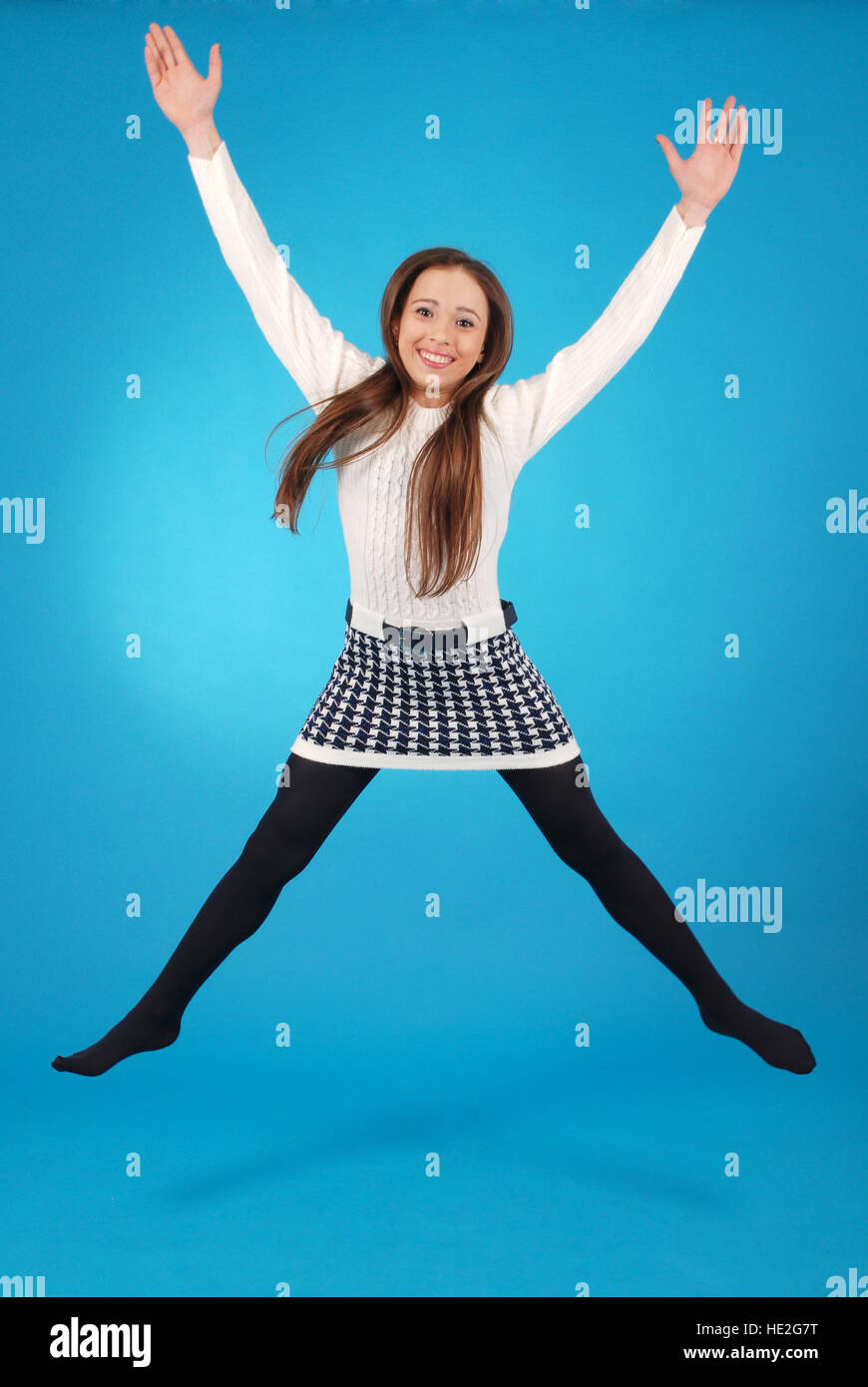Girl jumping isolated on blue studio background Stock Photo - Alamy