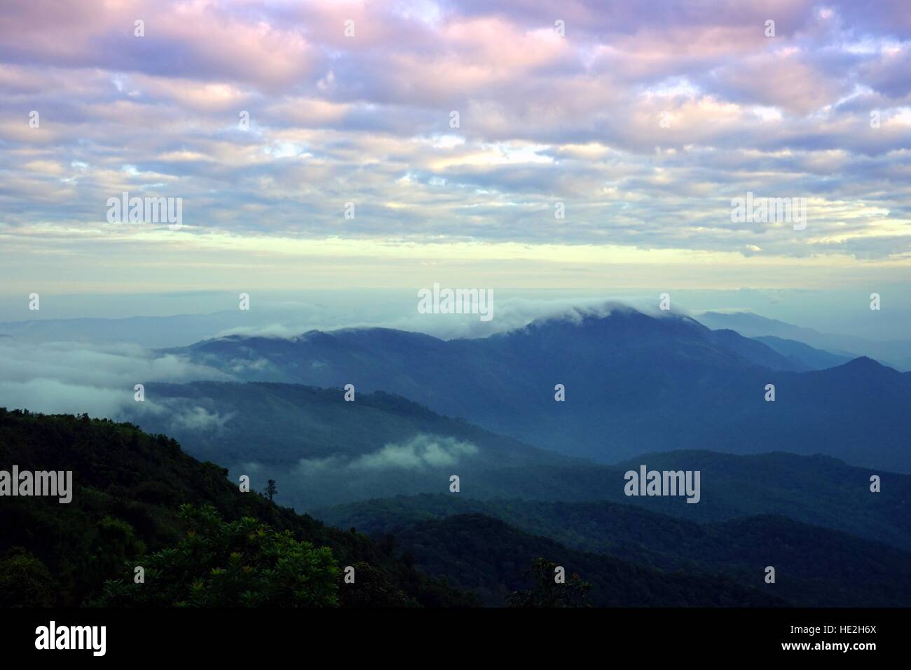 Mountain landscape with wave of fog and dark cloudy sky on the top of ...