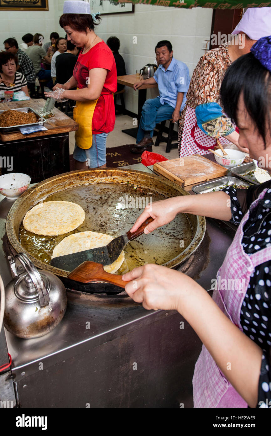 Hui uyghur woman preparing food Roast nang Flat Bread Muslim quarter ...