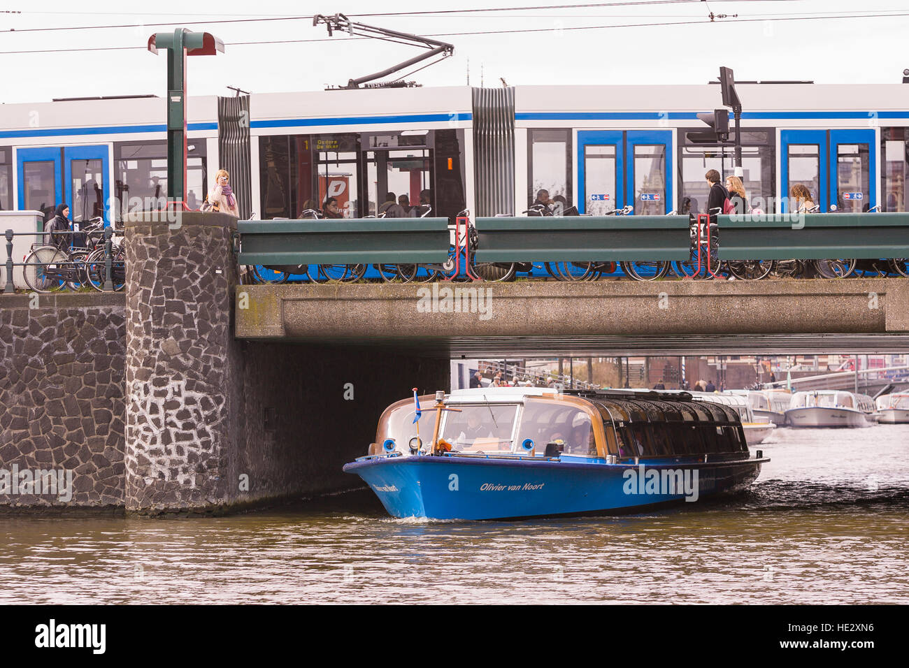 AMSTERDAM, NETHERLANDS - Canal boats goes under bridge as tram passes ...