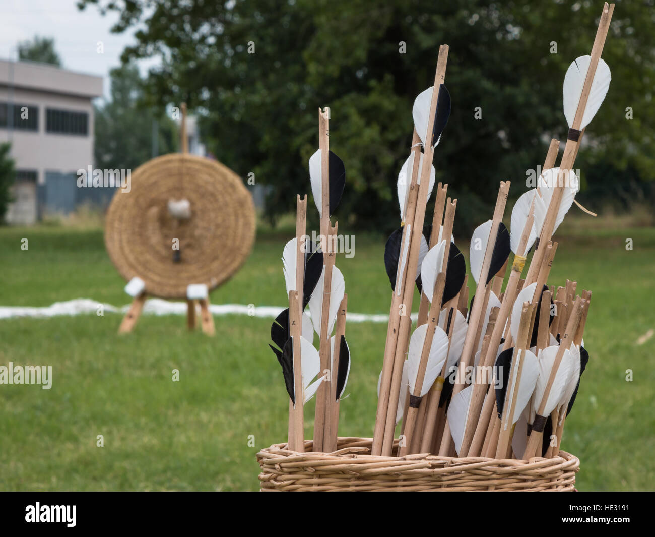Group of Arrows inside Wicker Basket and Straw Archery Target in ...