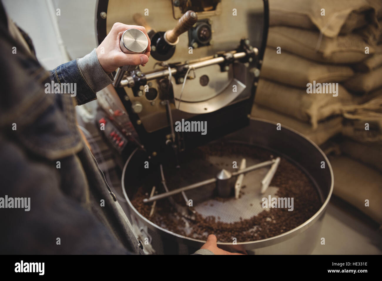 Mid-section of man grinding coffee beans in grinding machine in coffee ...