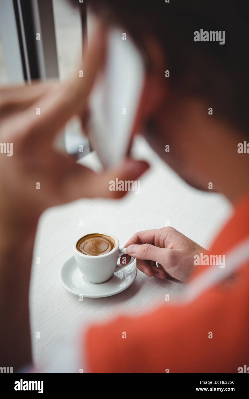 Man talking on mobile phone while having coffee in the coffee shop ...