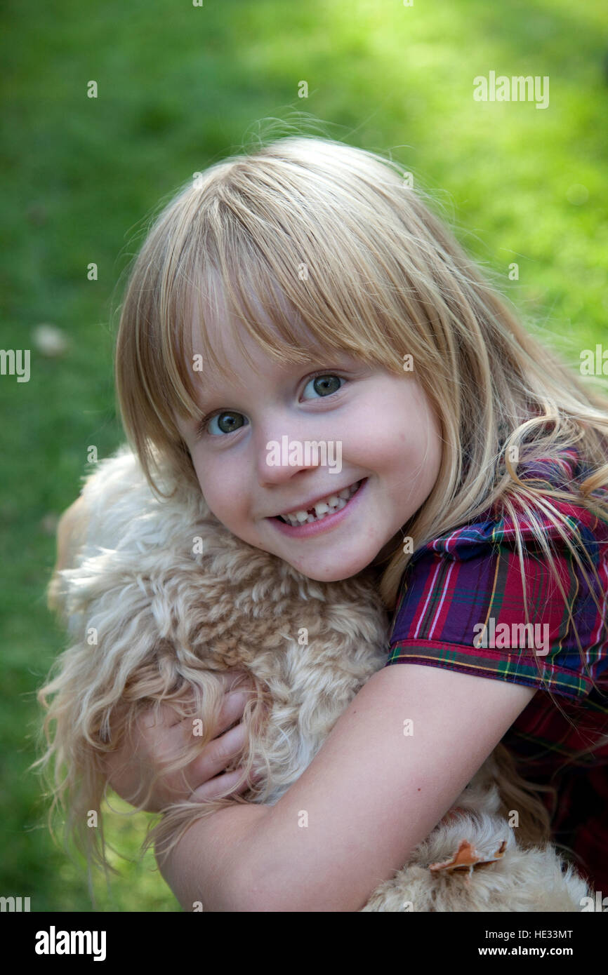 Young girl age 5 hugs her beloved Goldendoodle dog Gunnar. Clitherall ...
