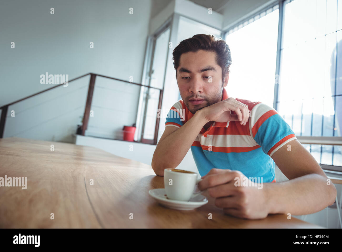 Thoughtful man sitting with cup of coffee on table in coffee shop Stock ...